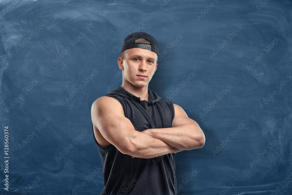 Young strong man standing in front of an empty blackboard with his arms ...