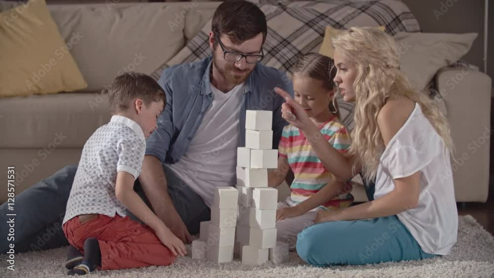 Parents and their little kids building a tower of toy bricks, son ...