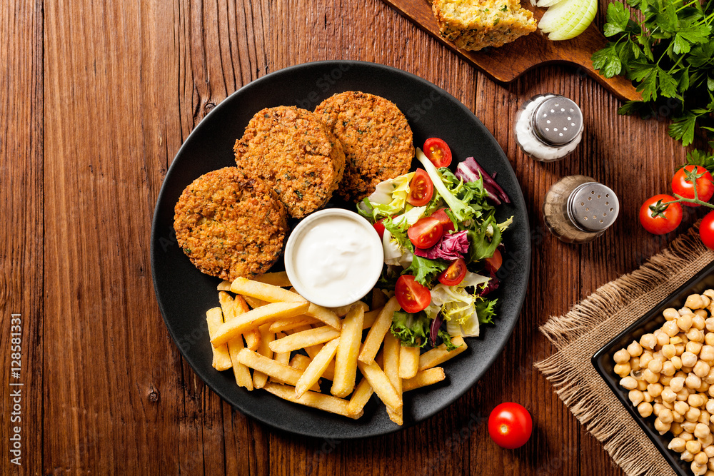 Serving of falafel and chips served on a black plate with sauce. Stock ...