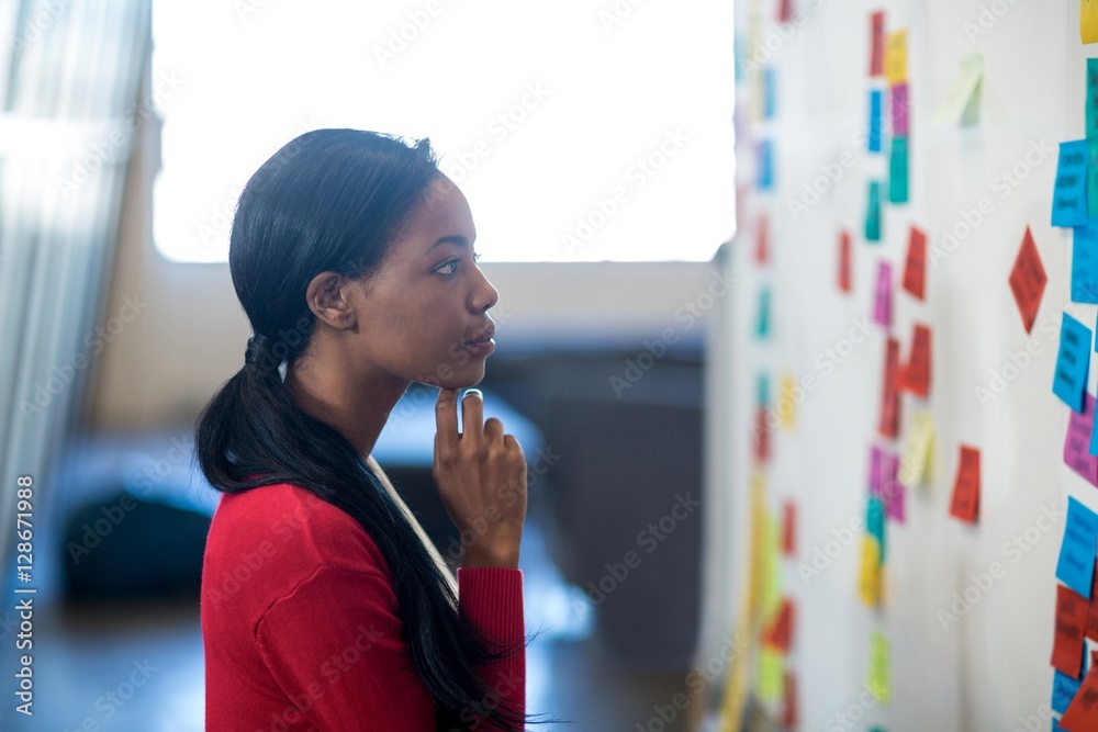 Young woman reading sticky notes on white board Stock Photo | Adobe Stock
