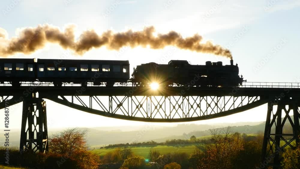 romantic scenery of steam engine locomotive crossing bridge at sunset ...