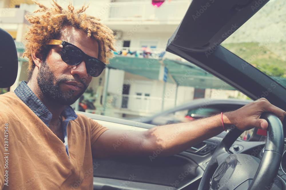 Young happy black man with dread locks wearing sunglasses sitting in ...