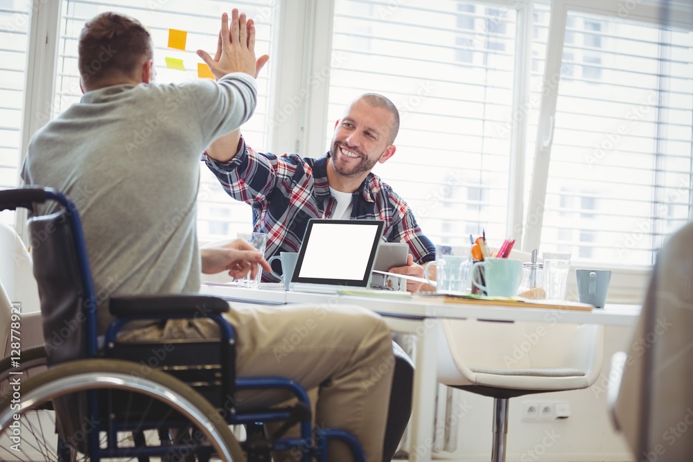Handicap businessman giving high-five to colleague in office Stock ...