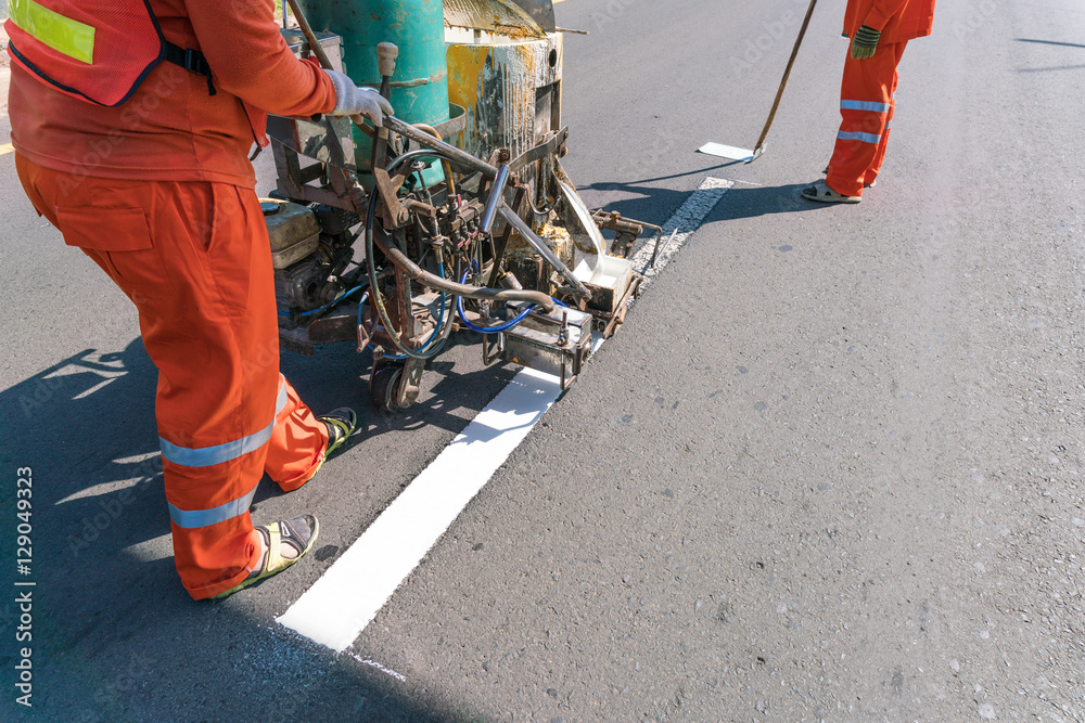 Thermoplastic spray marking machine during road construction. Worker ...