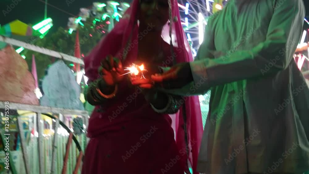 Indian couple in traditional dress with fire sparkle cracker at Diwali ...