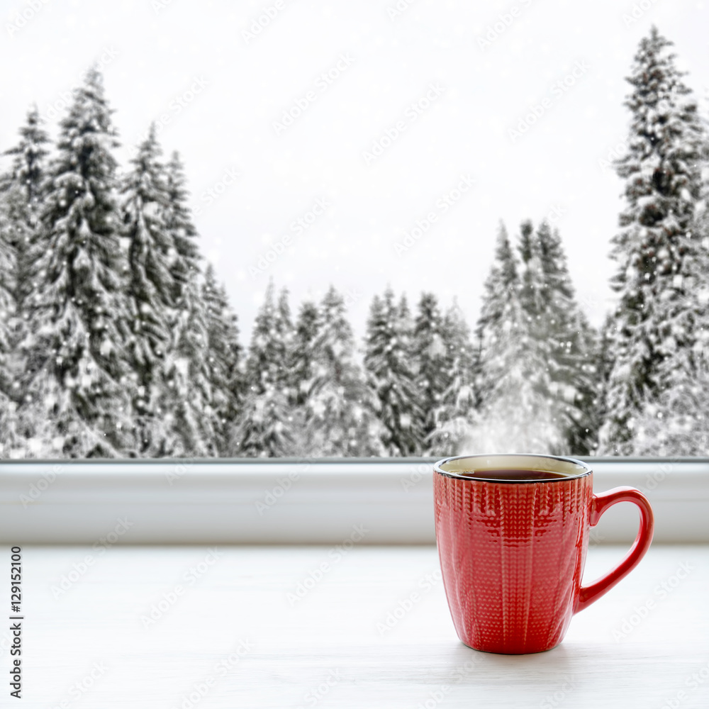 Coffee cup on a window sill. In the background, a beautiful winter ...