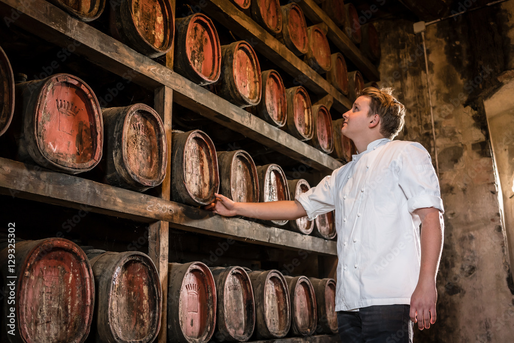 Chef in wine cellar full of vin santo dessert wine in oak barrels Stock ...