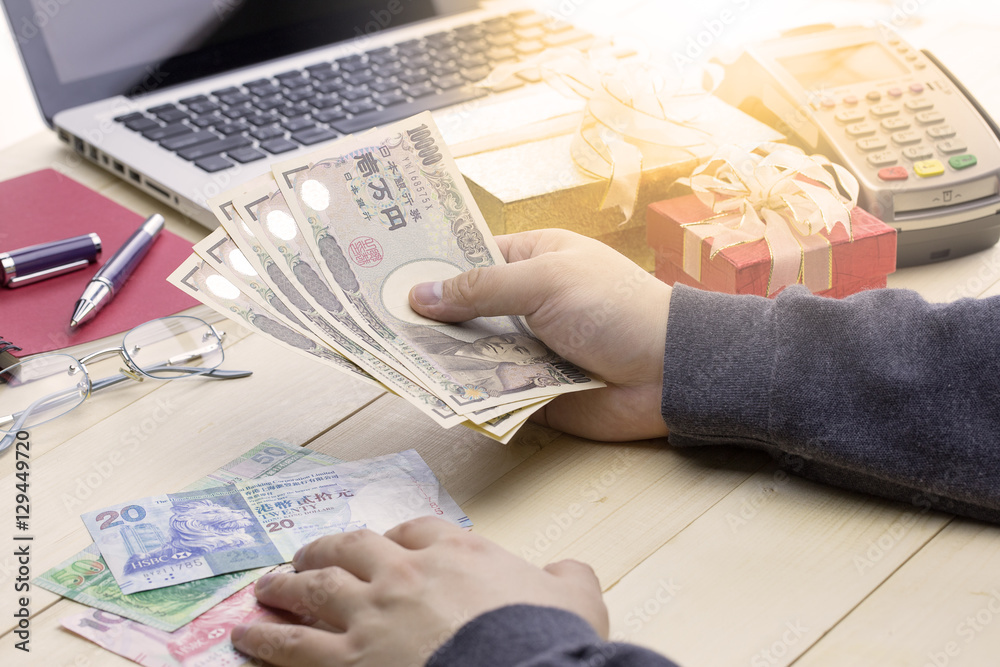 Cashier hand holding a Japanese bank notes on his desk with EDC ...