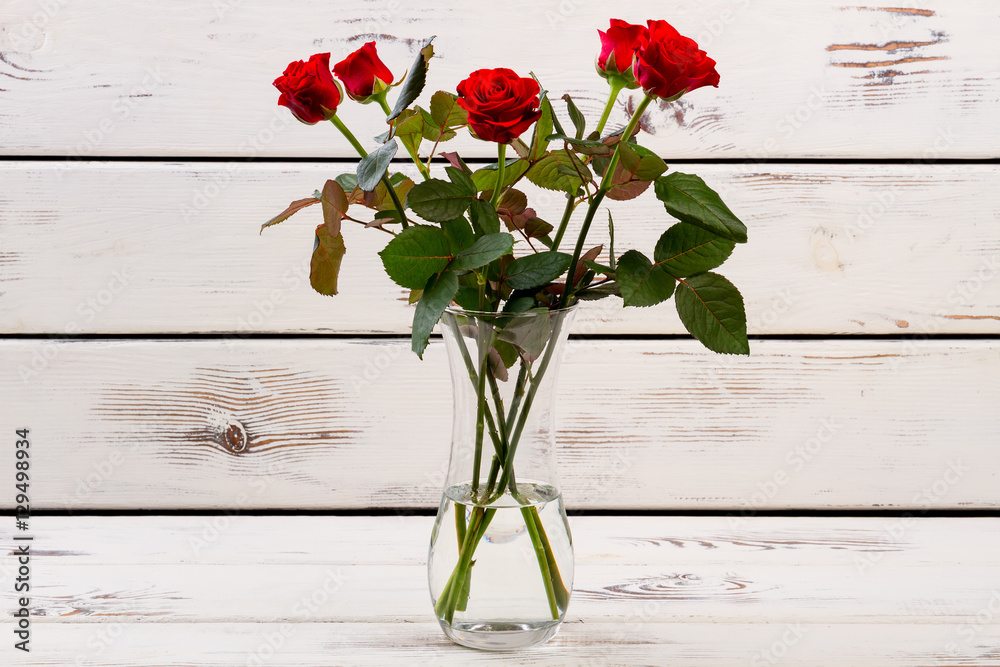 Red roses in glass vase. Flowers on light wooden background. Tender ...