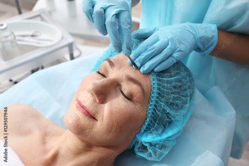 Surgeon operating female patient with scalpel at beauty salon Stock ...