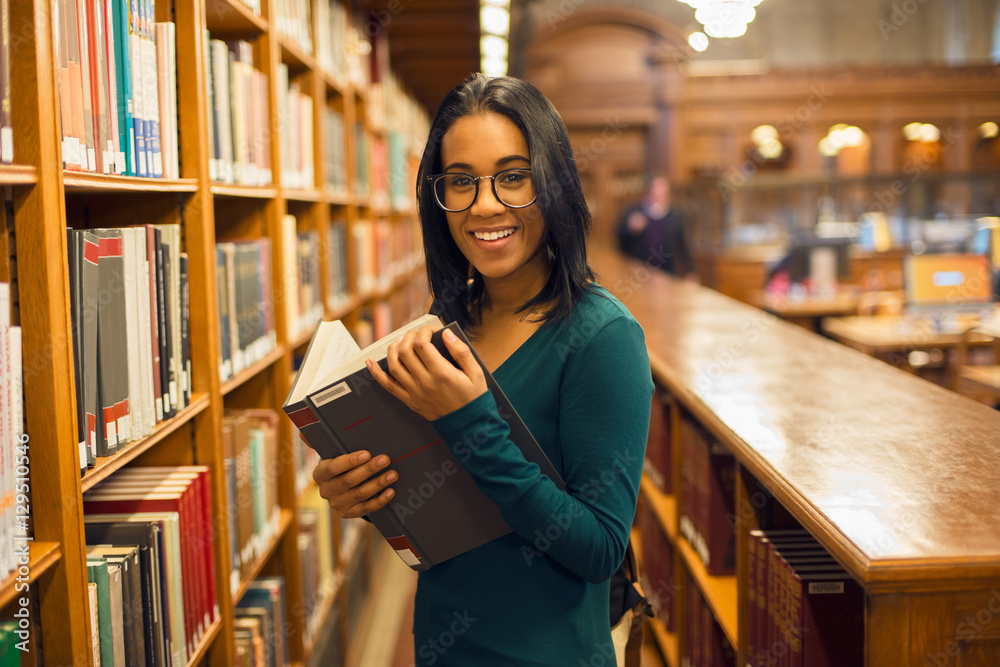 Happy smiling african american student girl reading book at library ... Happy smiling african american student girl reading book at library ...