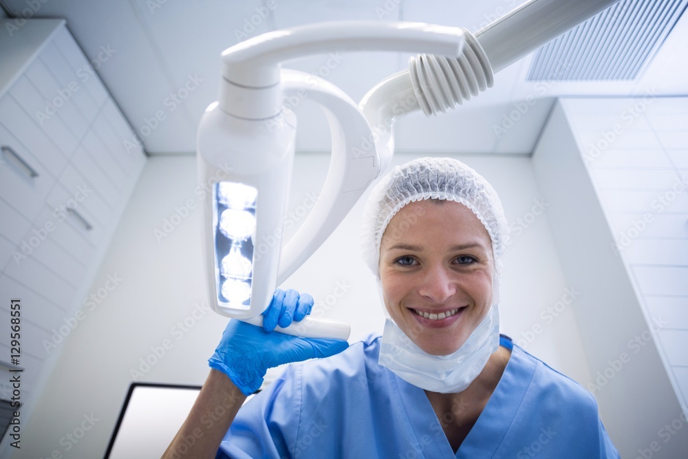 Dental assistant smiling at camera beside light Stock-Foto | Adobe Stock