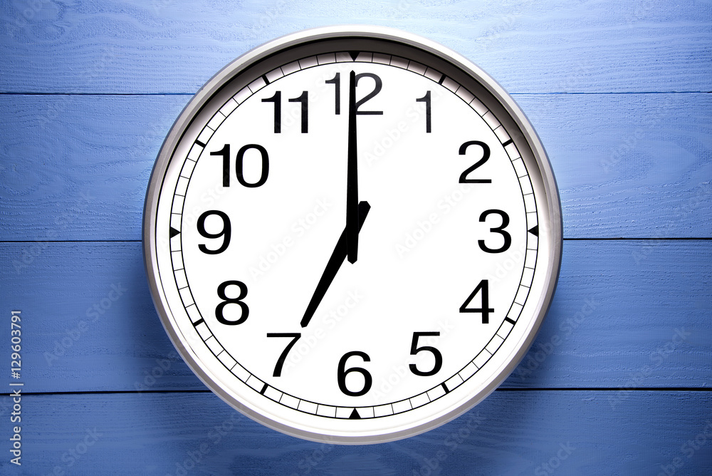 Round clock shows shows at 7 o'clock, clock on blue background Stock ...