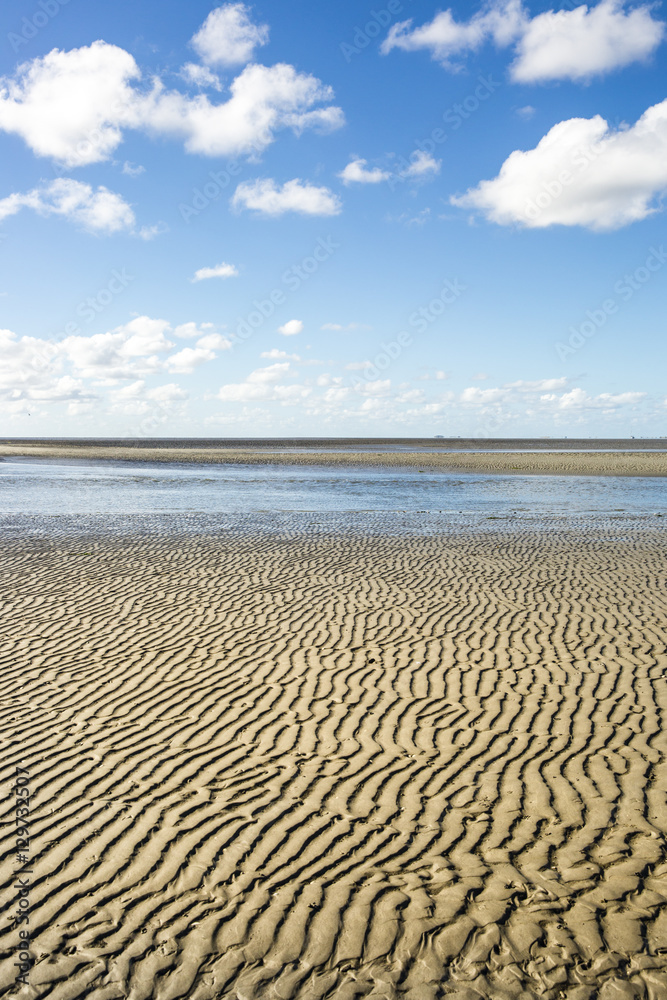 Maritime landscape with blue sky white clouds and pattern in the sand ...