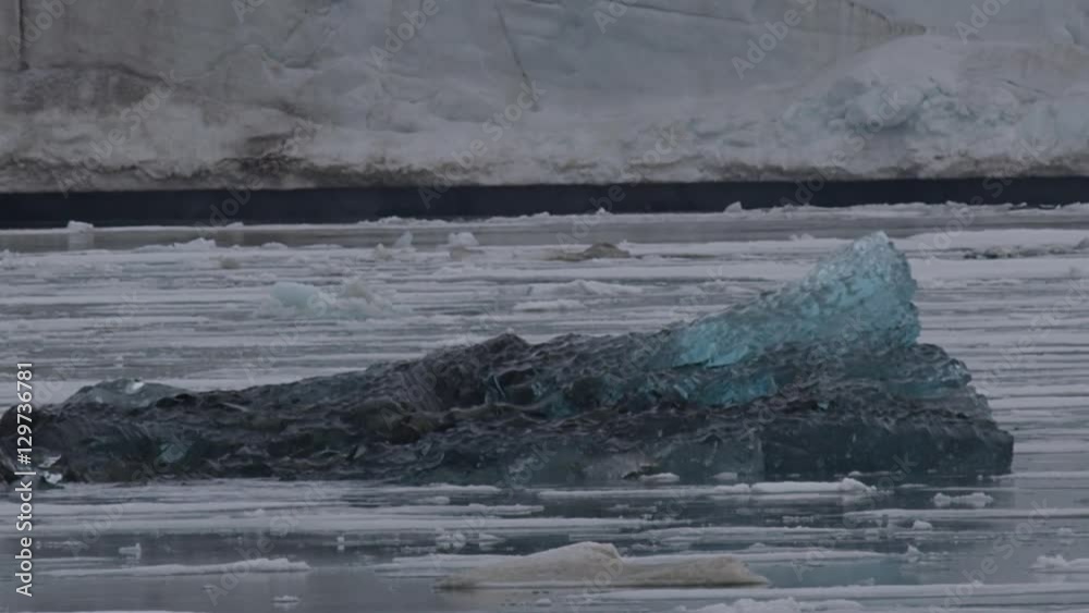 Clear sea ice glows blue while floating in the arctic sea around ...
