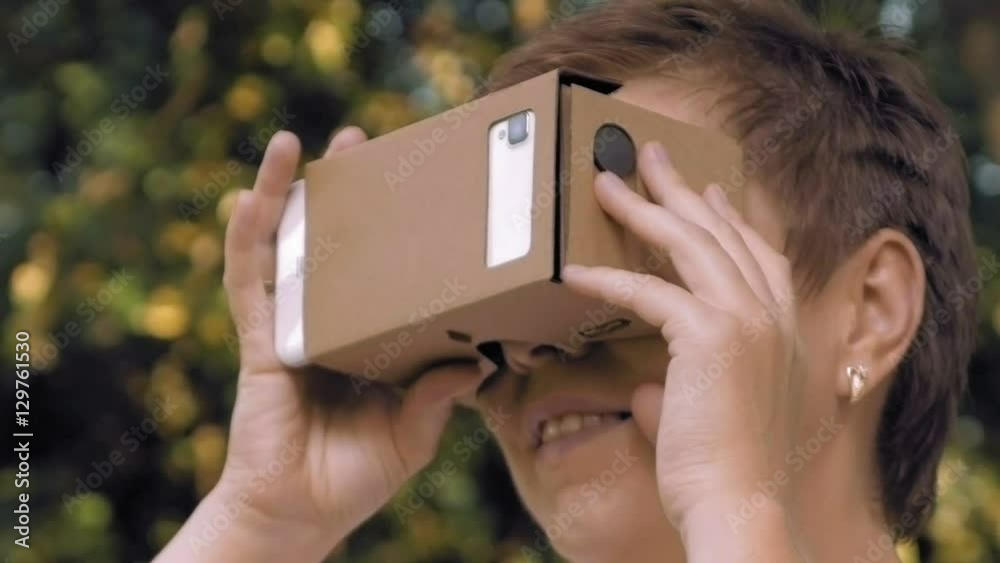 Woman explores virtual reality using cardboard VR glasses. Augmented ...
