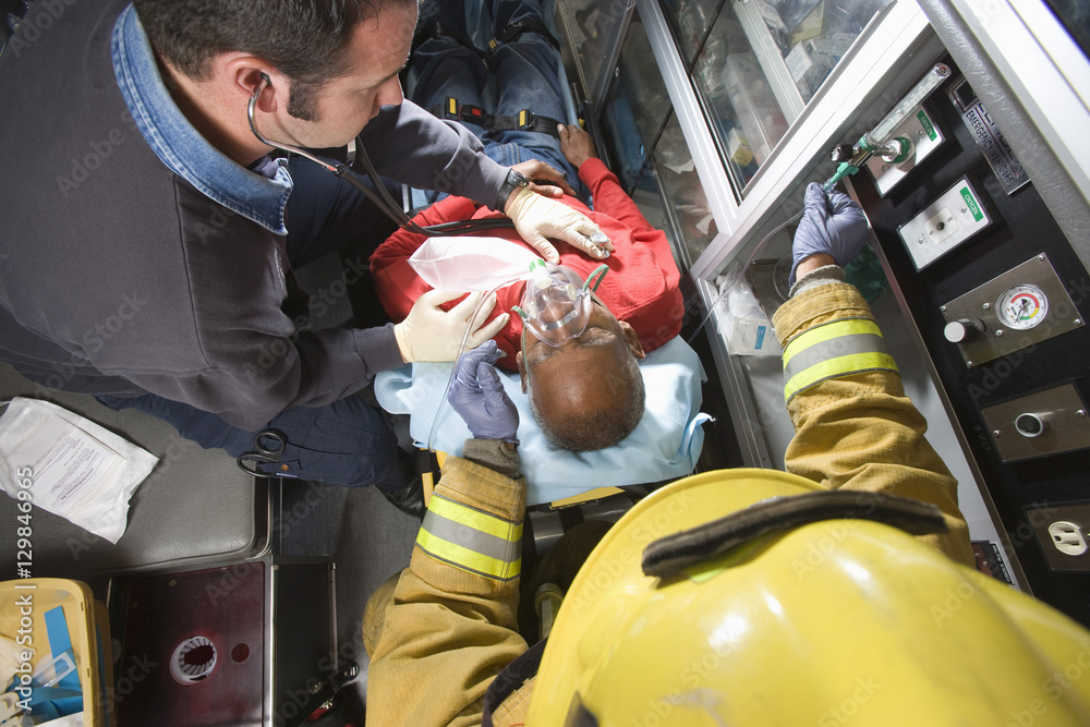 Male firefighter and EMT doctor taking care of an injured senior man in ...
