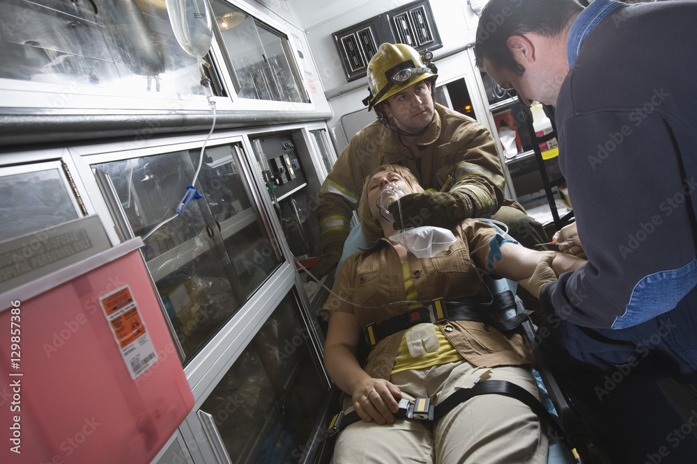 Firefighter and EMT doctor helping an injured woman in ambulance Stock ...