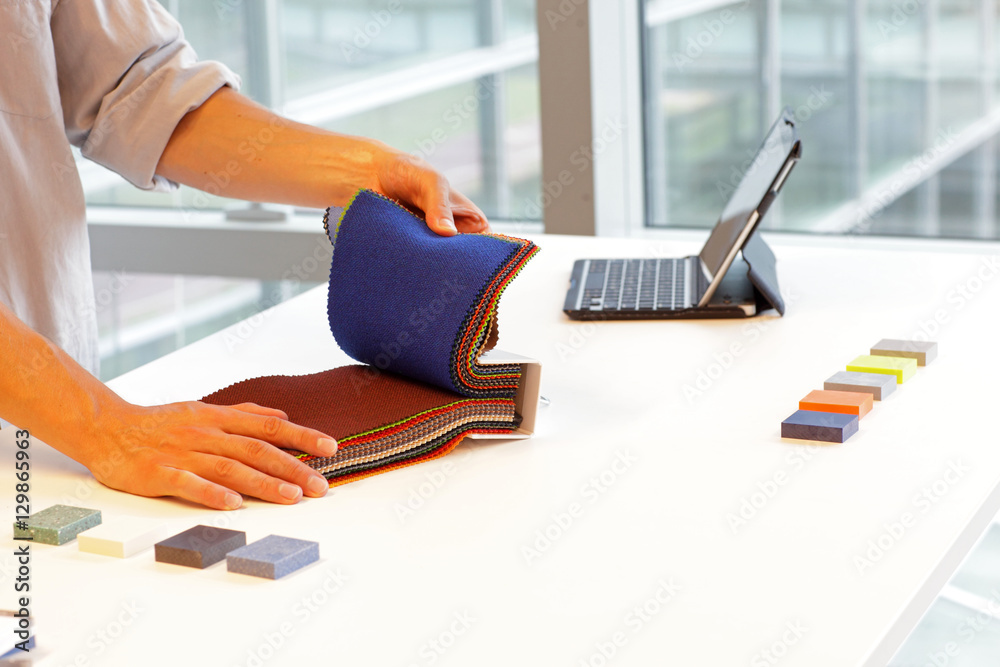 design - hands looking through color fabric swatches on desk with ...