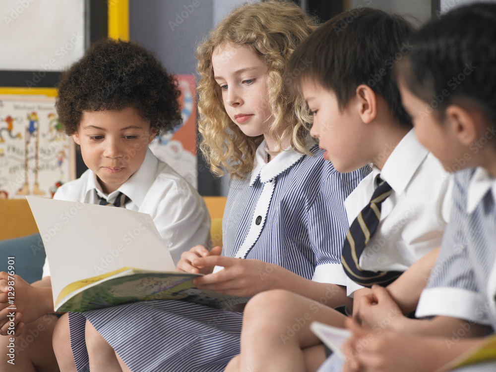 Row of elementary students reading book sitting in classroom Stock ...