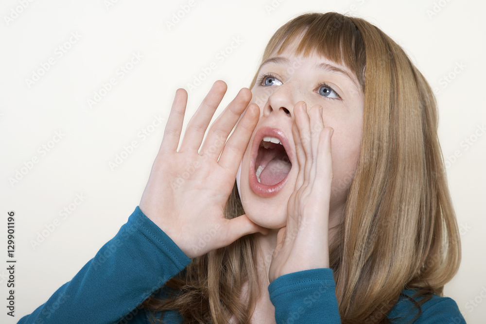 Closeup of a teenage girl shouting with hands cupped around mouth ...