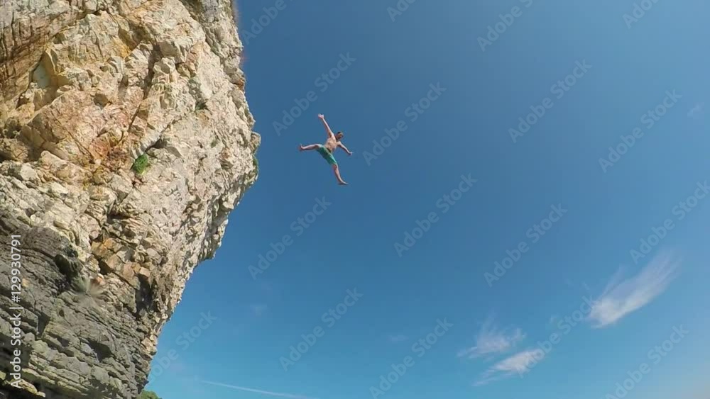 SLOW MOTION UNDERWATER: Happy man jumping off a high ocean cliff into ...