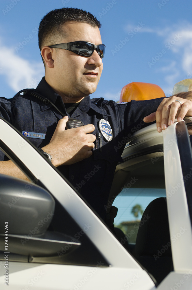 Male police officer using two-way radio while leaning on car Stock ...