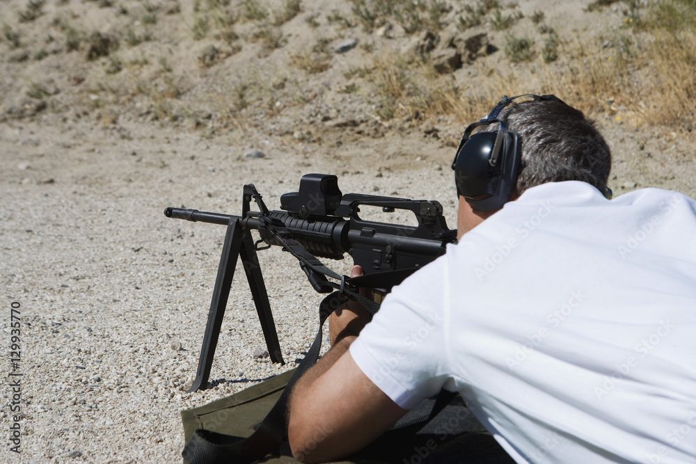 Man lying on ground aims machine gun at firing range Stock Photo ...