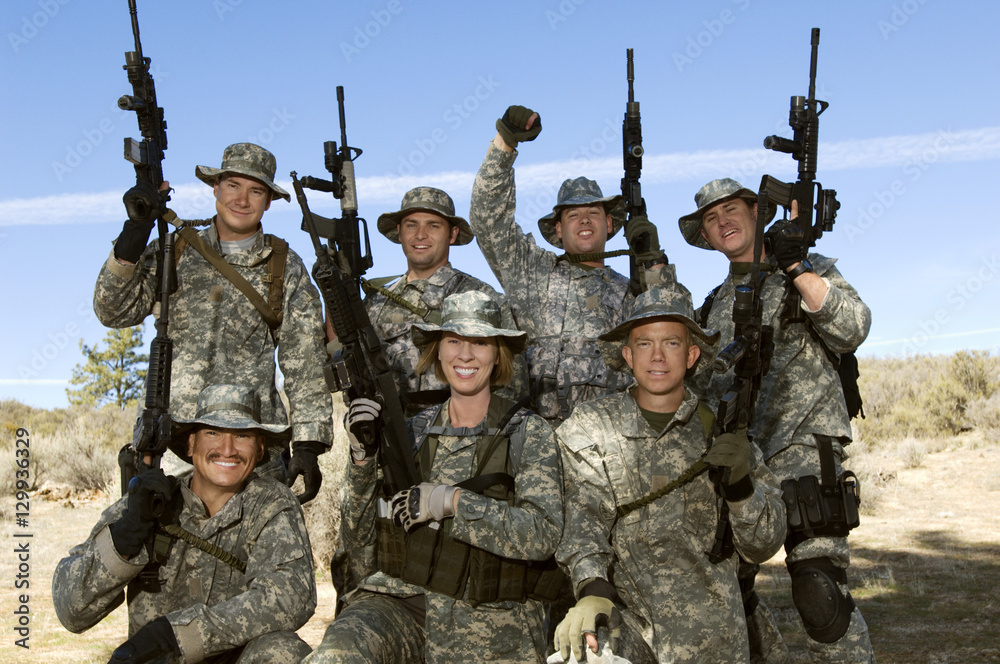 Group portrait of happy US military soldiers with weapons on field ...