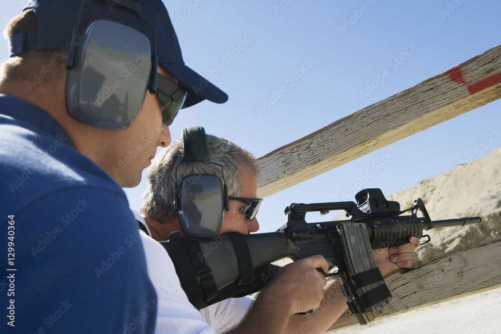 Instructor with man aiming machine gun at firing range during combat ...