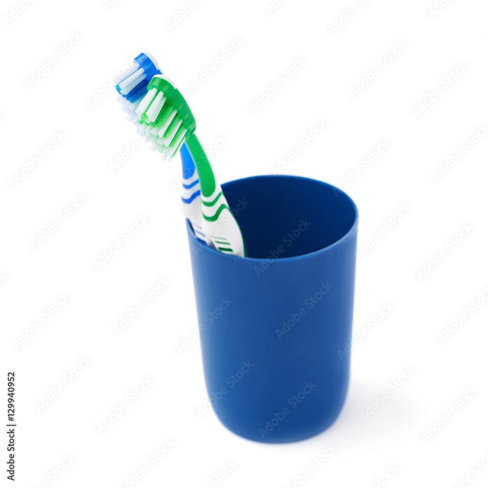 Pair of toothbrushes in blue plastic cup isolated over white background ...