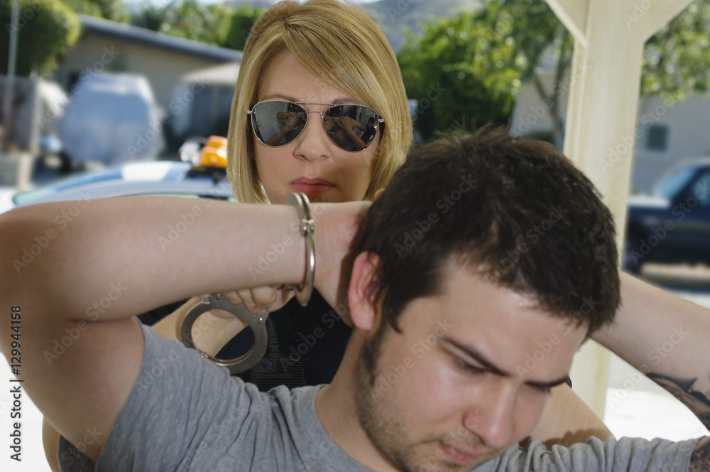 Female police officer arresting young man Stock Photo | Adobe Stock