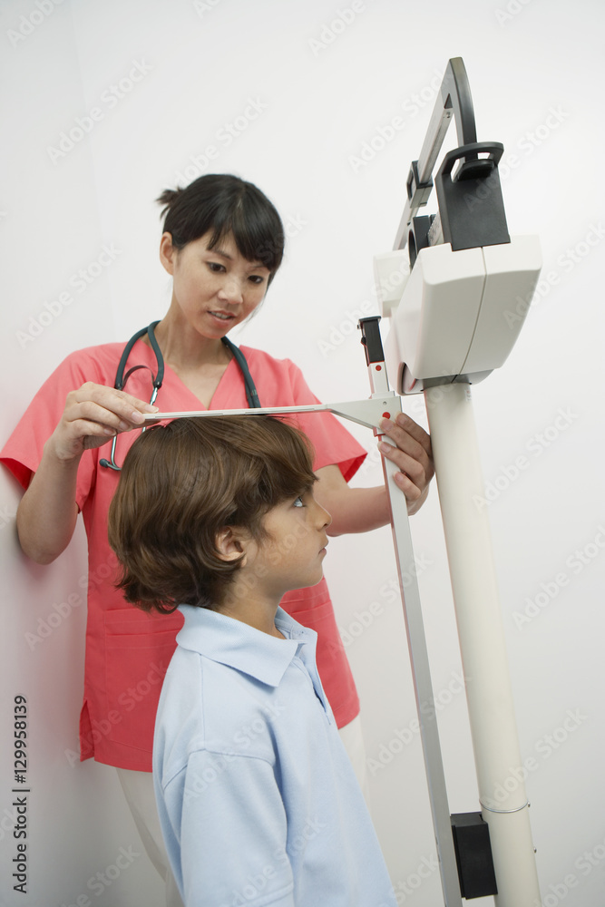 Female doctor measuring height of a preadolescent boy in the clinic ...