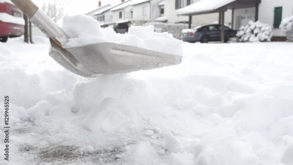 Slow motion clearing sidewalk and shoveling fresh snow off in suburban ...