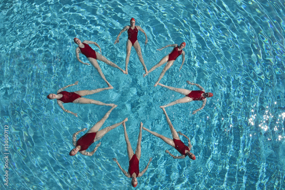 Foto de Group of synchronised swimmers forming a star shape in pool do ... Foto de Group of synchronised swimmers forming a star shape in pool do ...