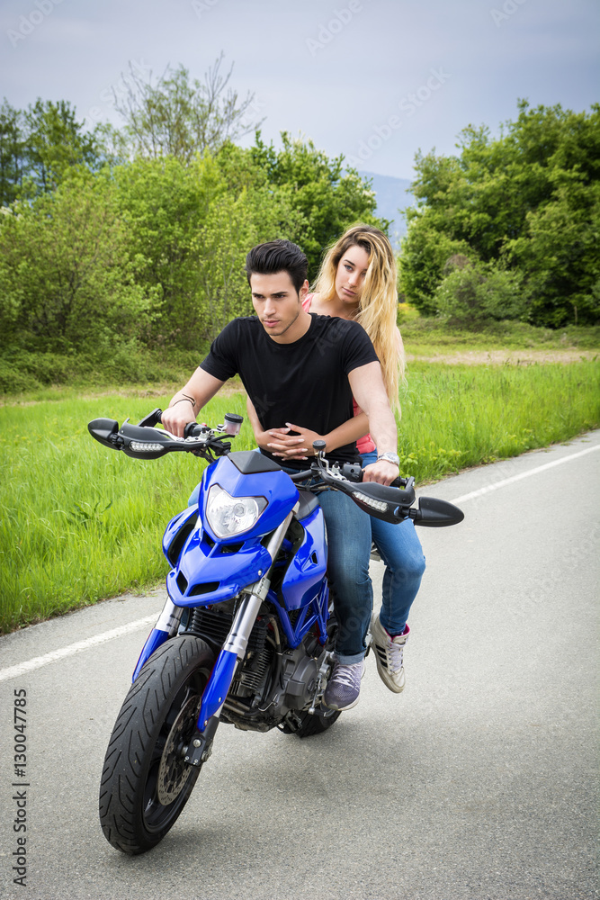 Handsome young man riding motorcycle with woman as passenger Stock ...