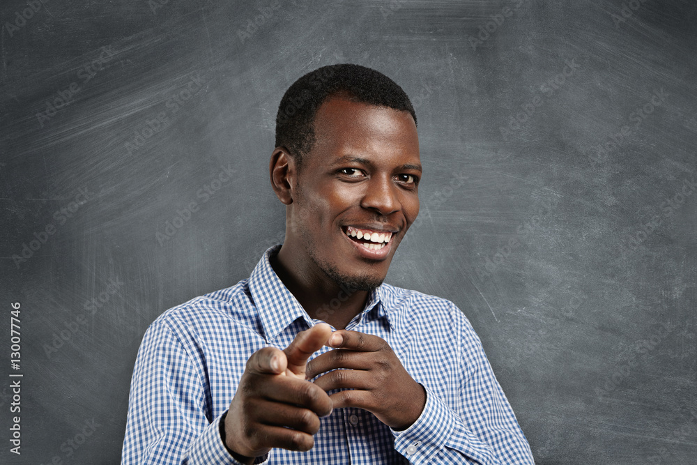Funny young African customer smiling happily and pointing his index ...