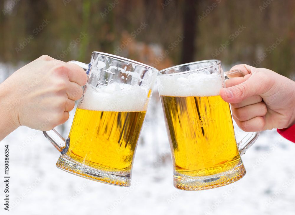 Clinking Beer glasses on winter forest background. New year celebration ...