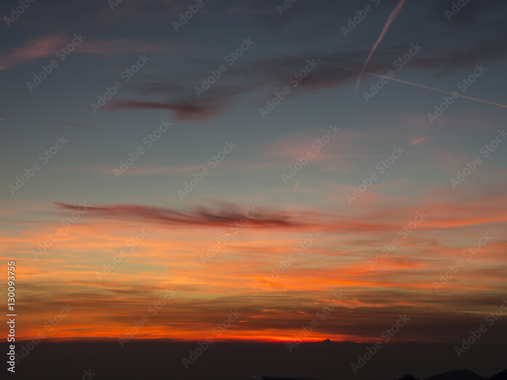 Fiery sunset from mountain pick with thin glazes in the sky evening ...