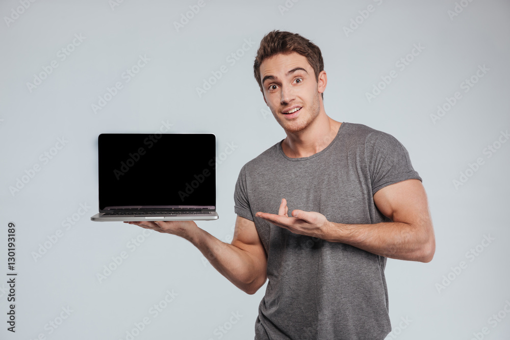 Portrait of a surprised man pointing on blank screen laptop Stock Photo ...