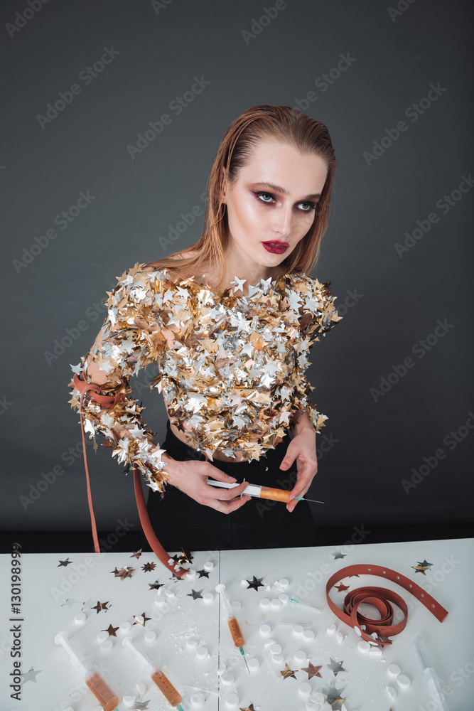Addicted pretty young woman standing and holding syringe with drugs ...