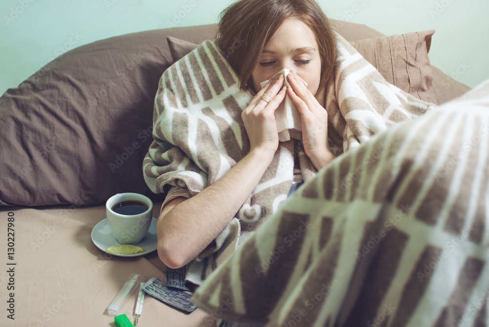 young woman sick with a cold lying in bed Stock Photo | Adobe Stock