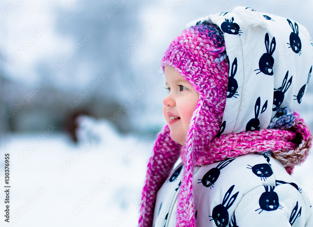 Child in snowy day. Baby girl in white snowsuite and pink hat, boots ...