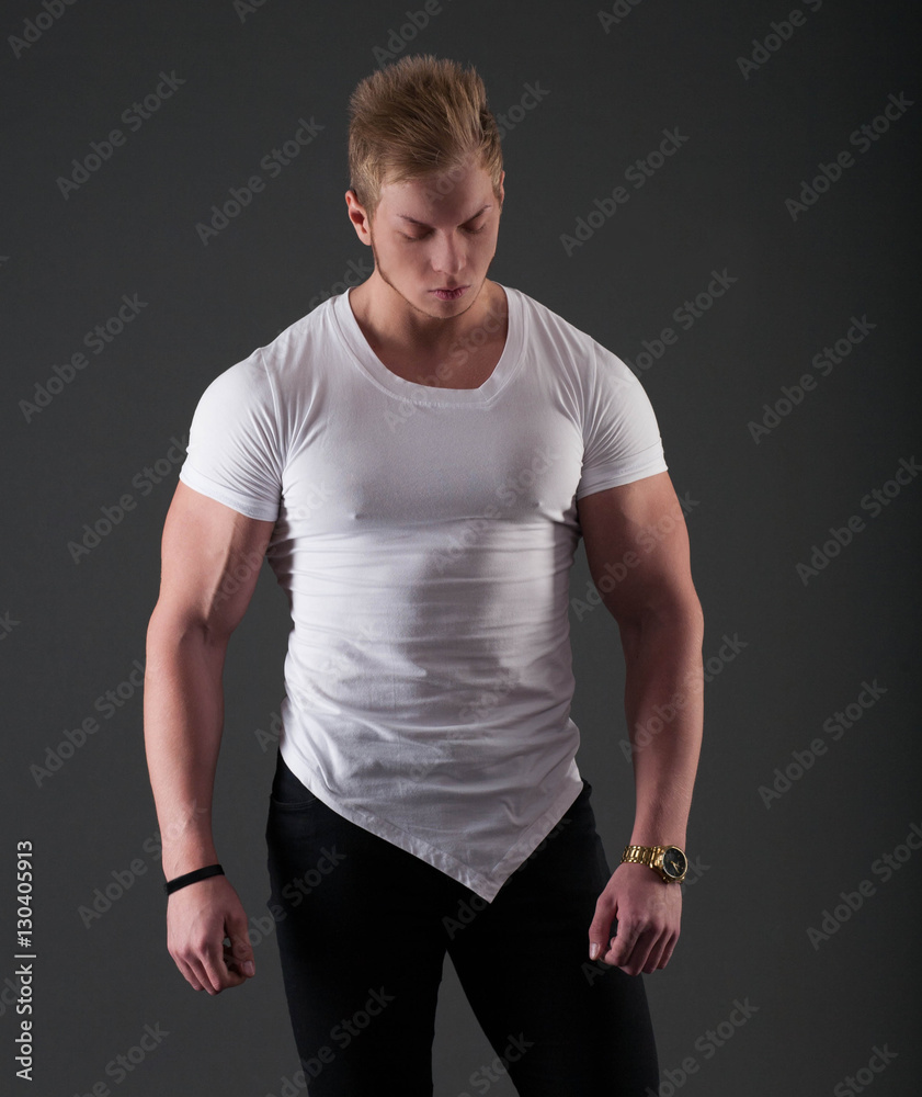 Portrait of handsome male athlete with biceps wearing asymmetric tshirt ...