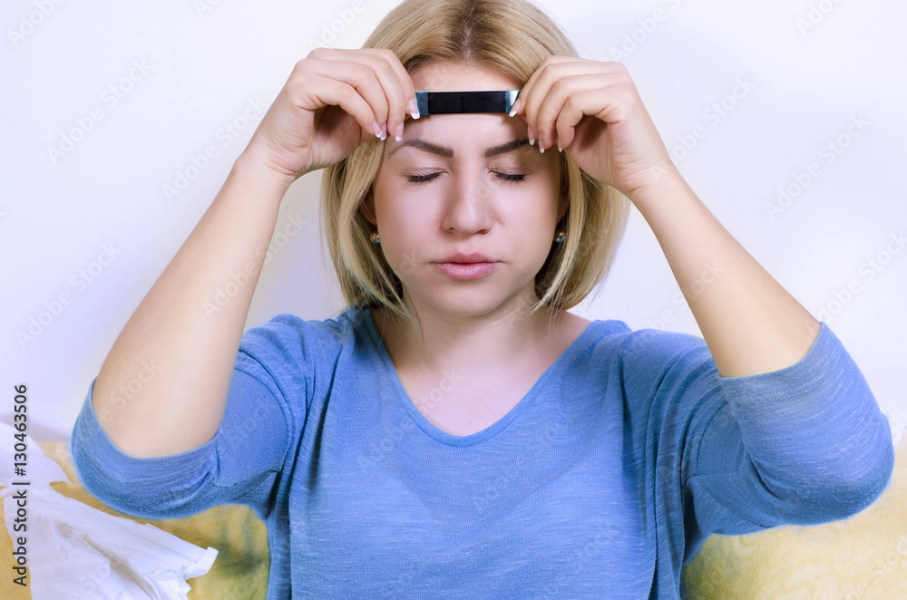Beautiful woman measuring body temperature with forehead thermometer ...