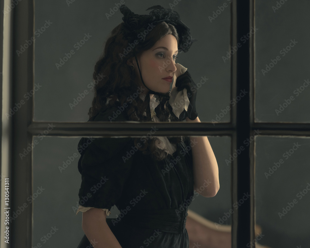 Sad retro victorian woman in black dress wiping tear standing be Stock ...