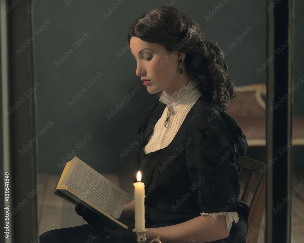 Retro victorian girl reading book by candlelight behind window. Stock ...