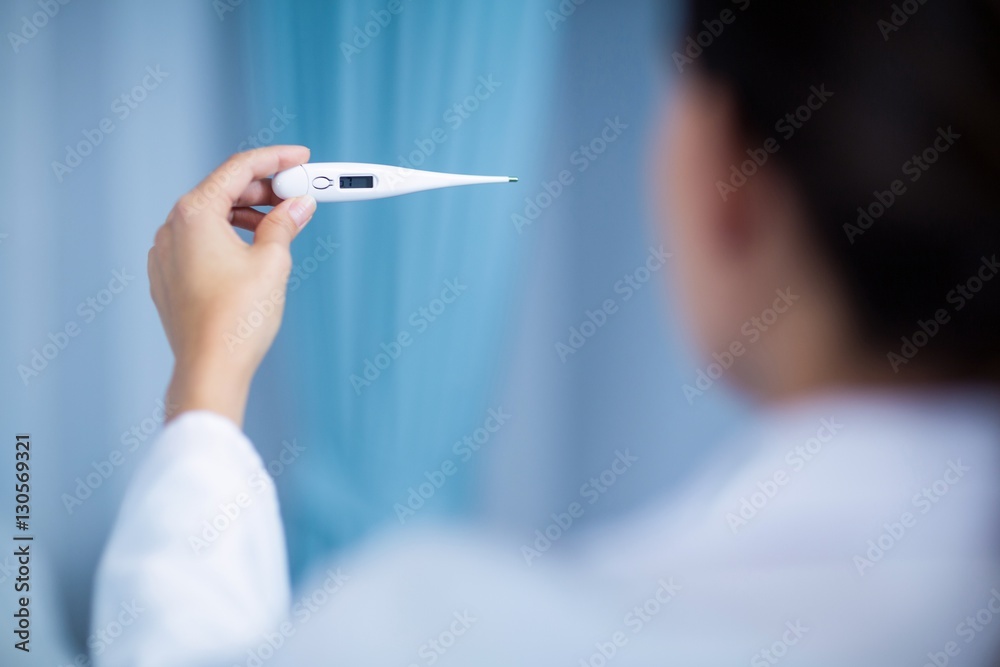 Female doctor checking fever from digital thermometer Stock Photo ...