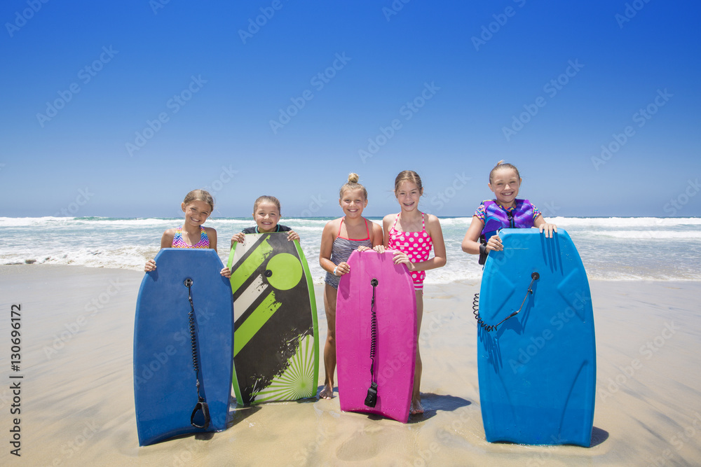 Foto de Cute group of kids standing by a boogie boards at the beach ...