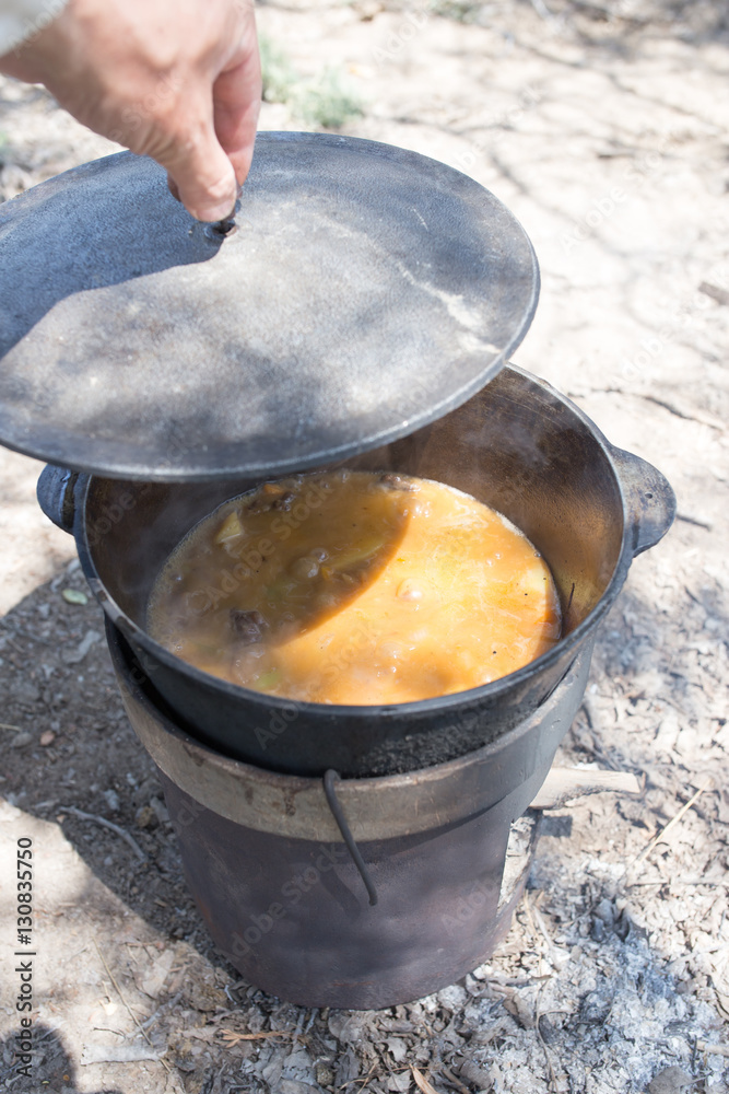 Foto Stock cooking in a cauldron on the nature | Adobe Stock